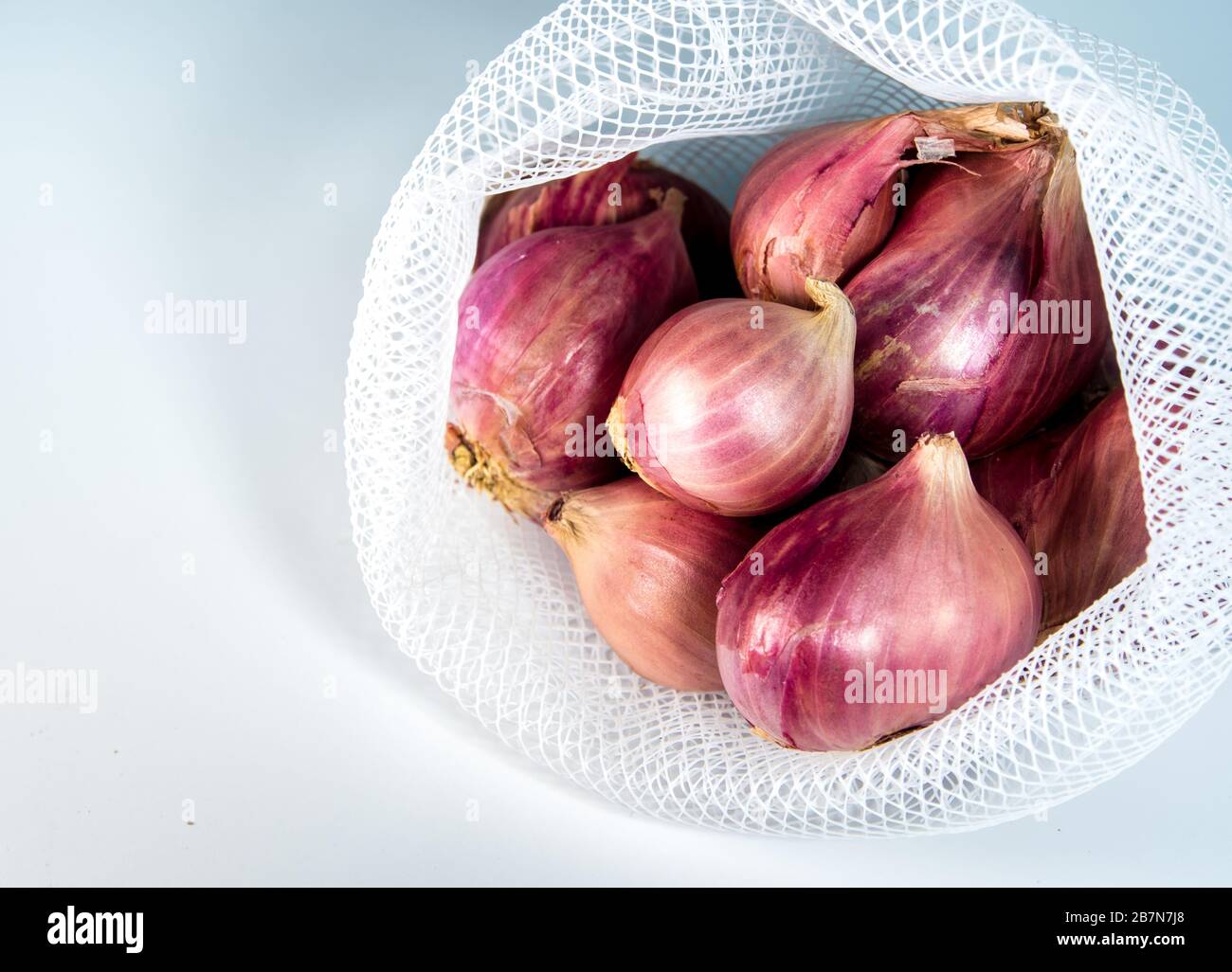 Red onions in mesh bag isolated on white background Stock Photo - Alamy