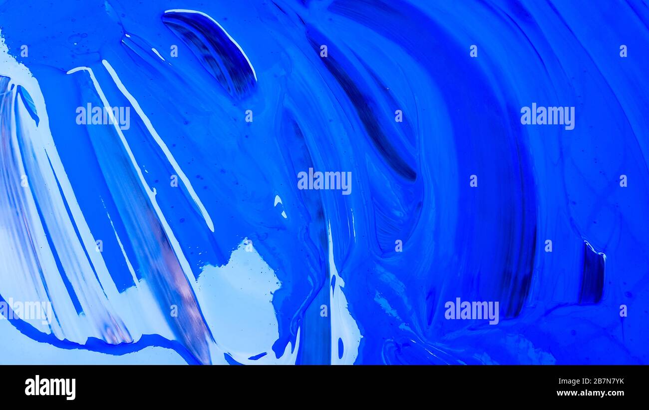 Abstract background of spilled blue paint with buckets on a black ...
