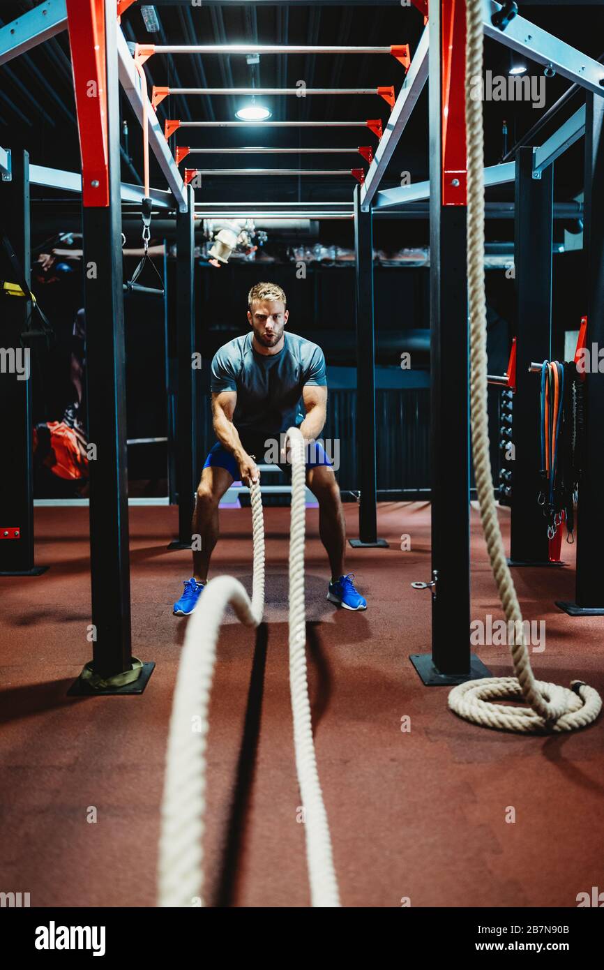 Happy fit men with battle ropes exercise in the fitness gym Stock Photo ...