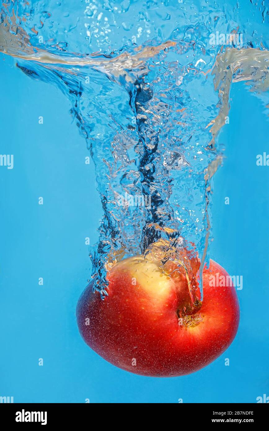 Fresh apple drops in water with splash on a blue background Stock Photo ...