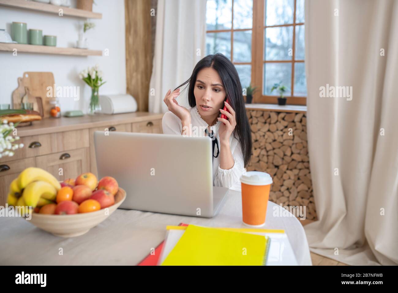 Young woman checking laptop, holding strand of hair Stock Photo - Alamy