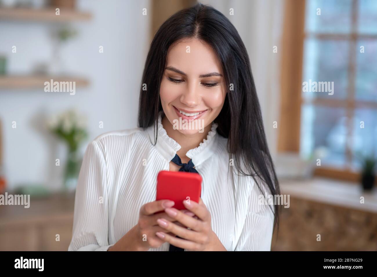 Young woman holding smartphone, checking something, smiling Stock Photo ...