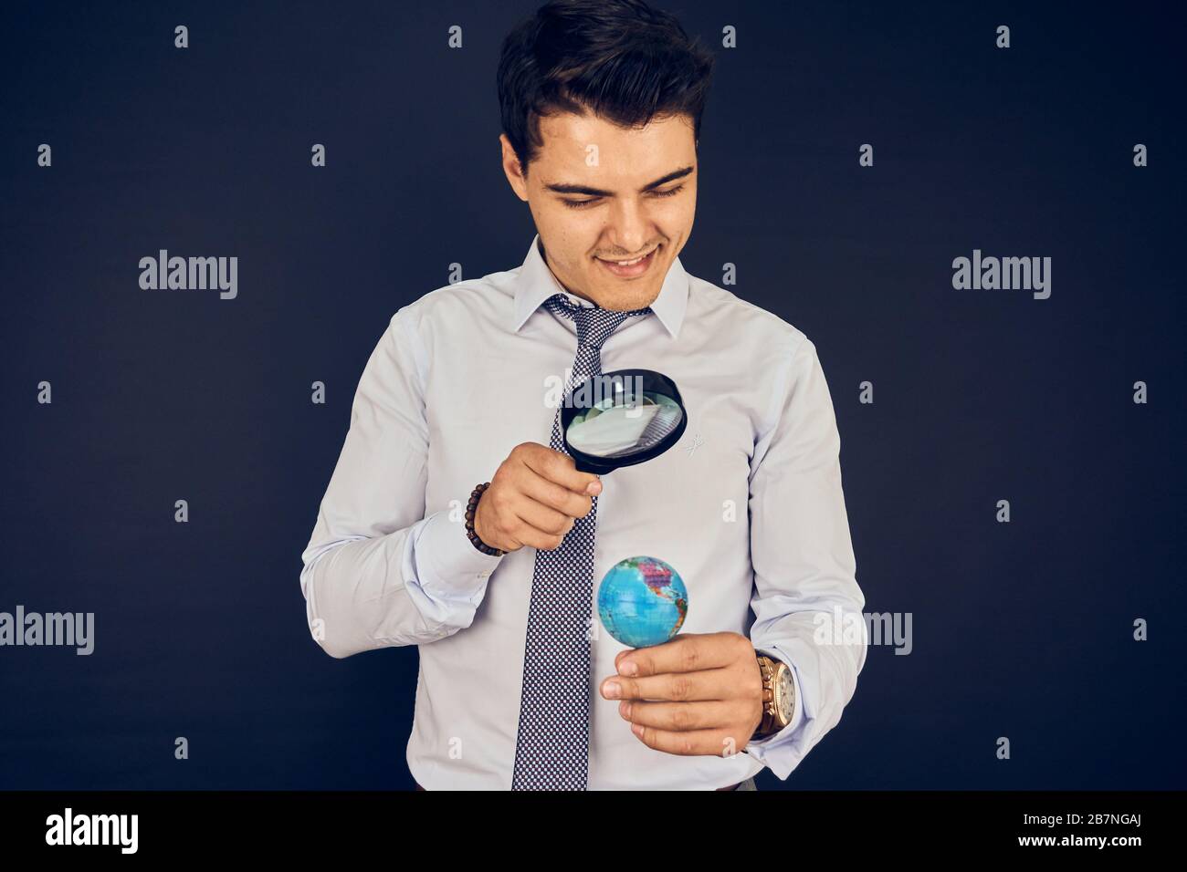 Young man examining world with magnifying glass Stock Photo - Alamy