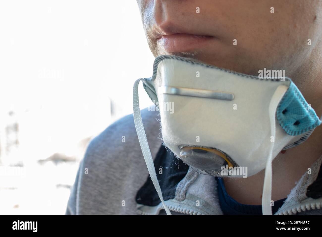 A man in a half-removed medical face mask. Respirator on the neck. Man ...