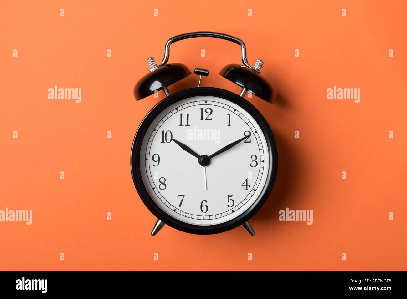 Black vintage alarm clock on orange background. Time concept Stock ...