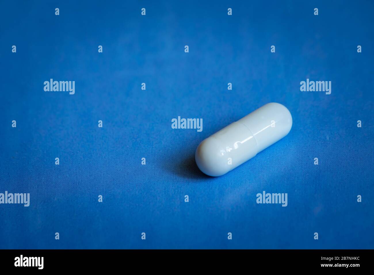A single medicine capsule lies on the blue table in close-up Stock ...