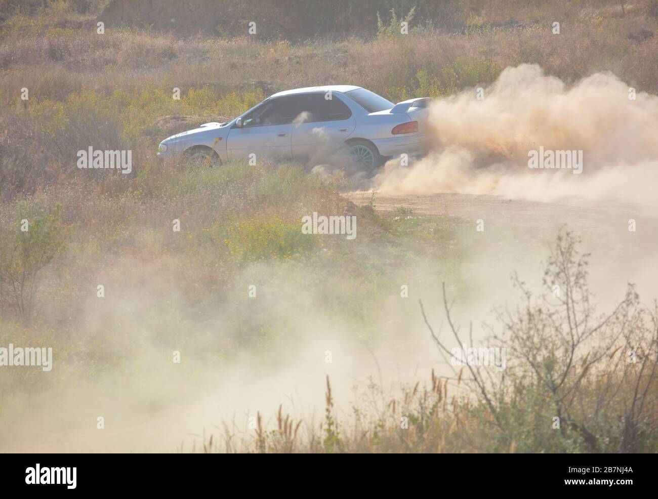 Summer dry dirt road. Sunny day. Racing car and a lot of dust on a ...