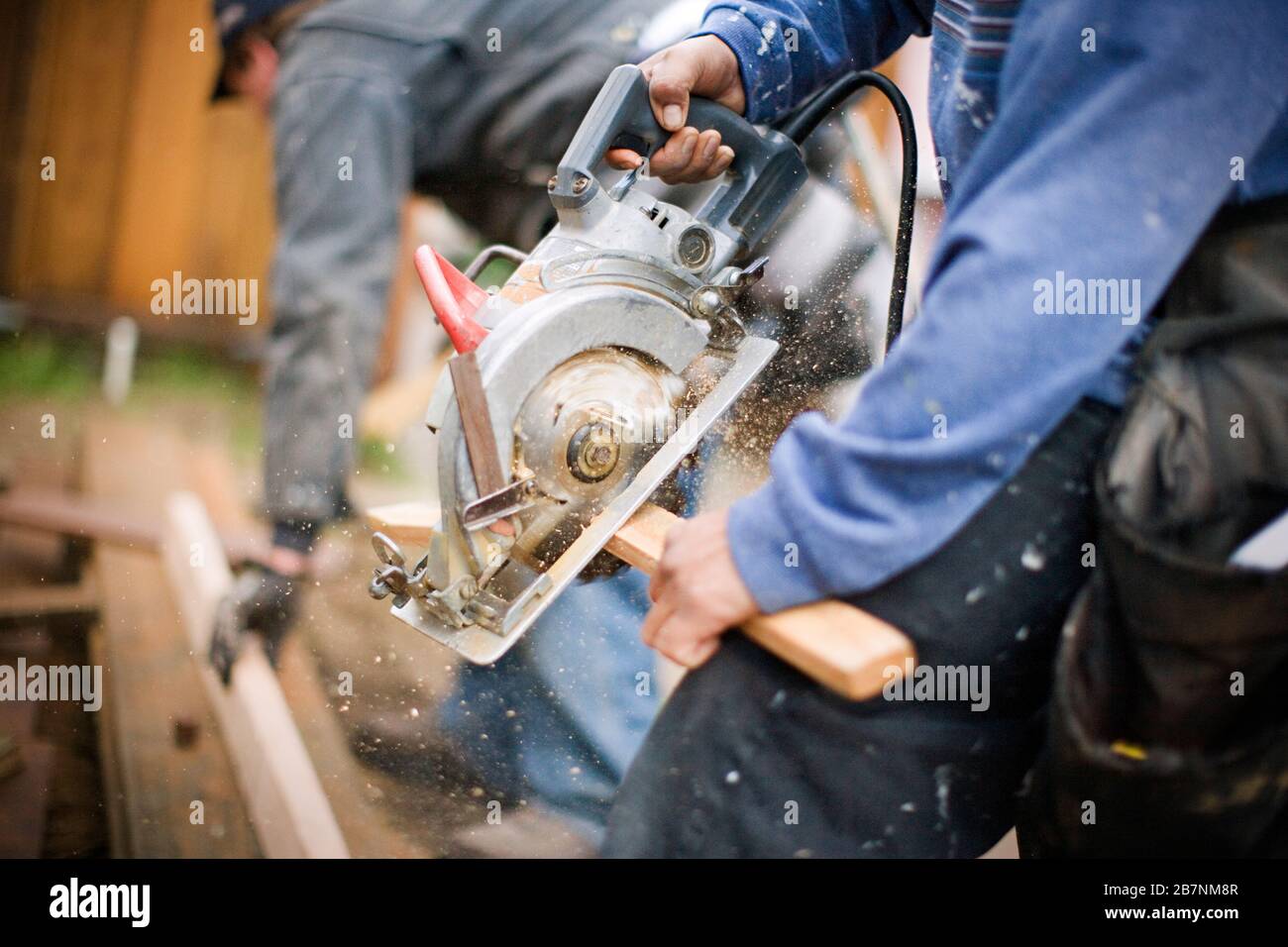 Construction worker cutting piece of wood with a rotary saw Stock Photo ...