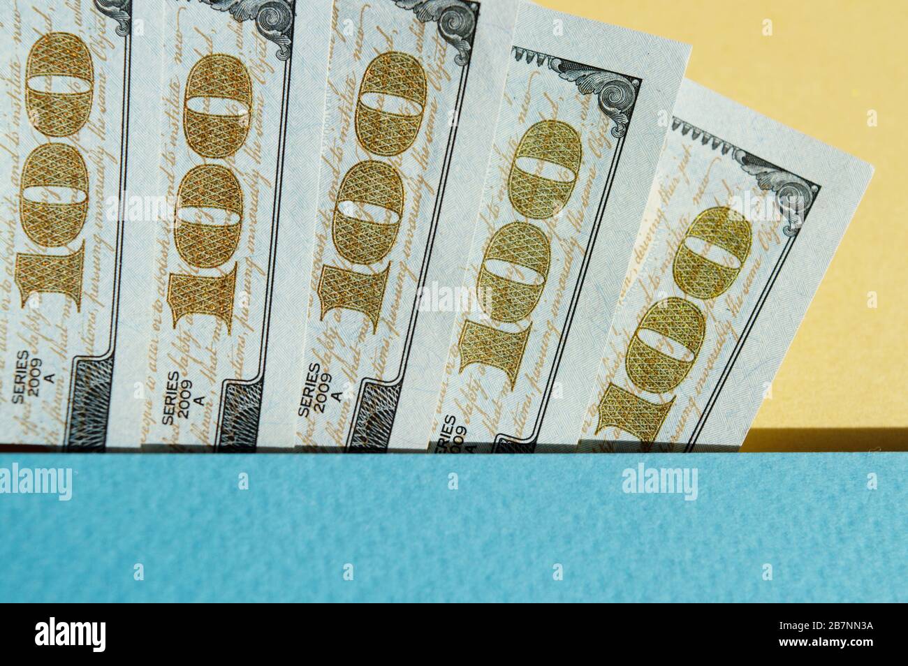 Five pieces of 100 dollar bills on the yellow and blue background ...