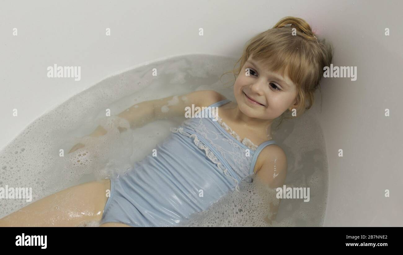 Attractive four years old girl takes a bath in swimwear. Hygiene for ...