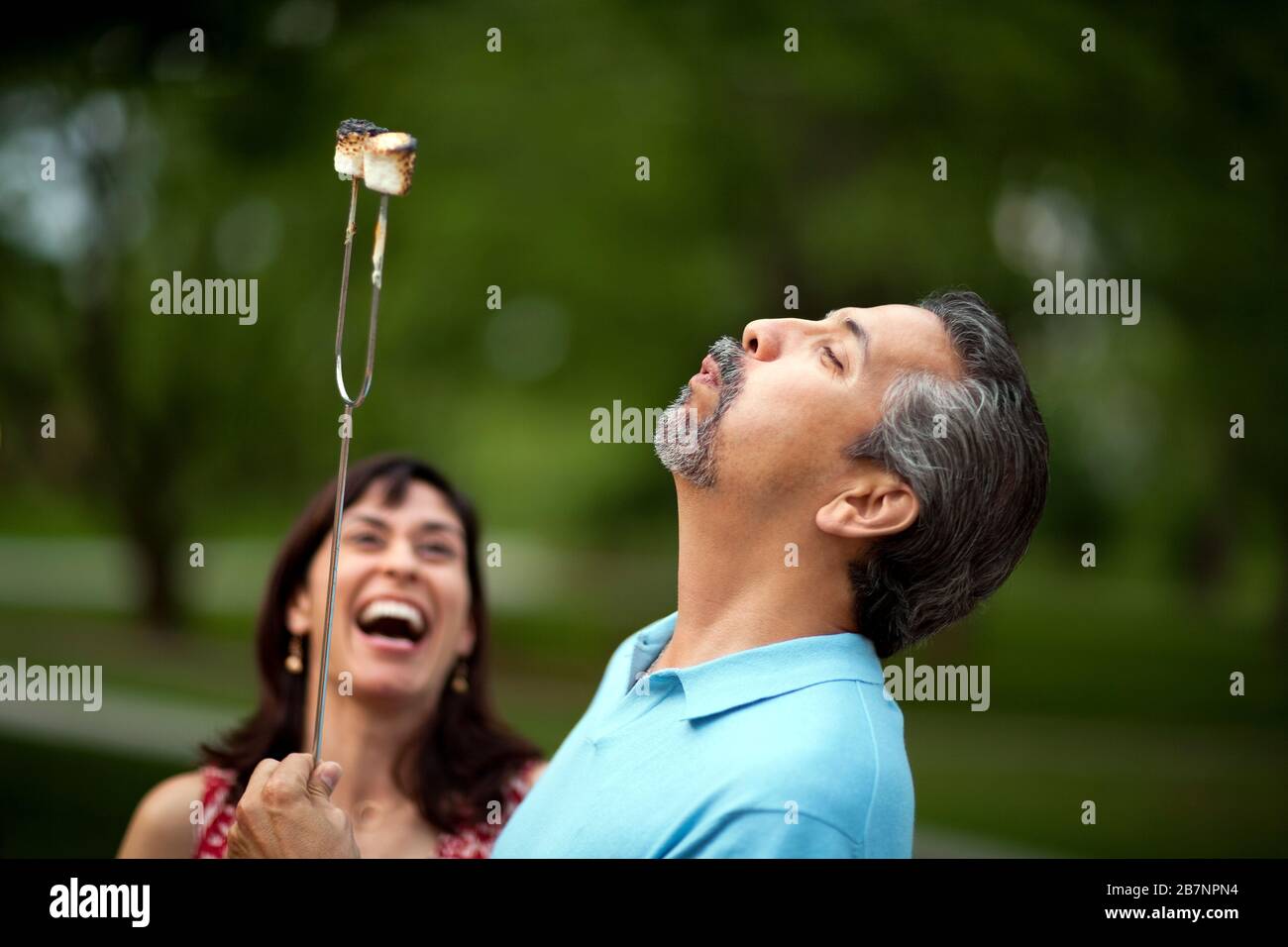 Middle-aged woman laughs in delight as her husband blows on the ...