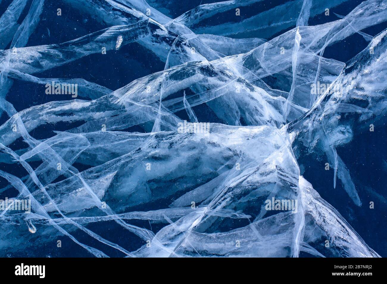 Beautiful patterns of cracks in blue transparent ice. The natural ...