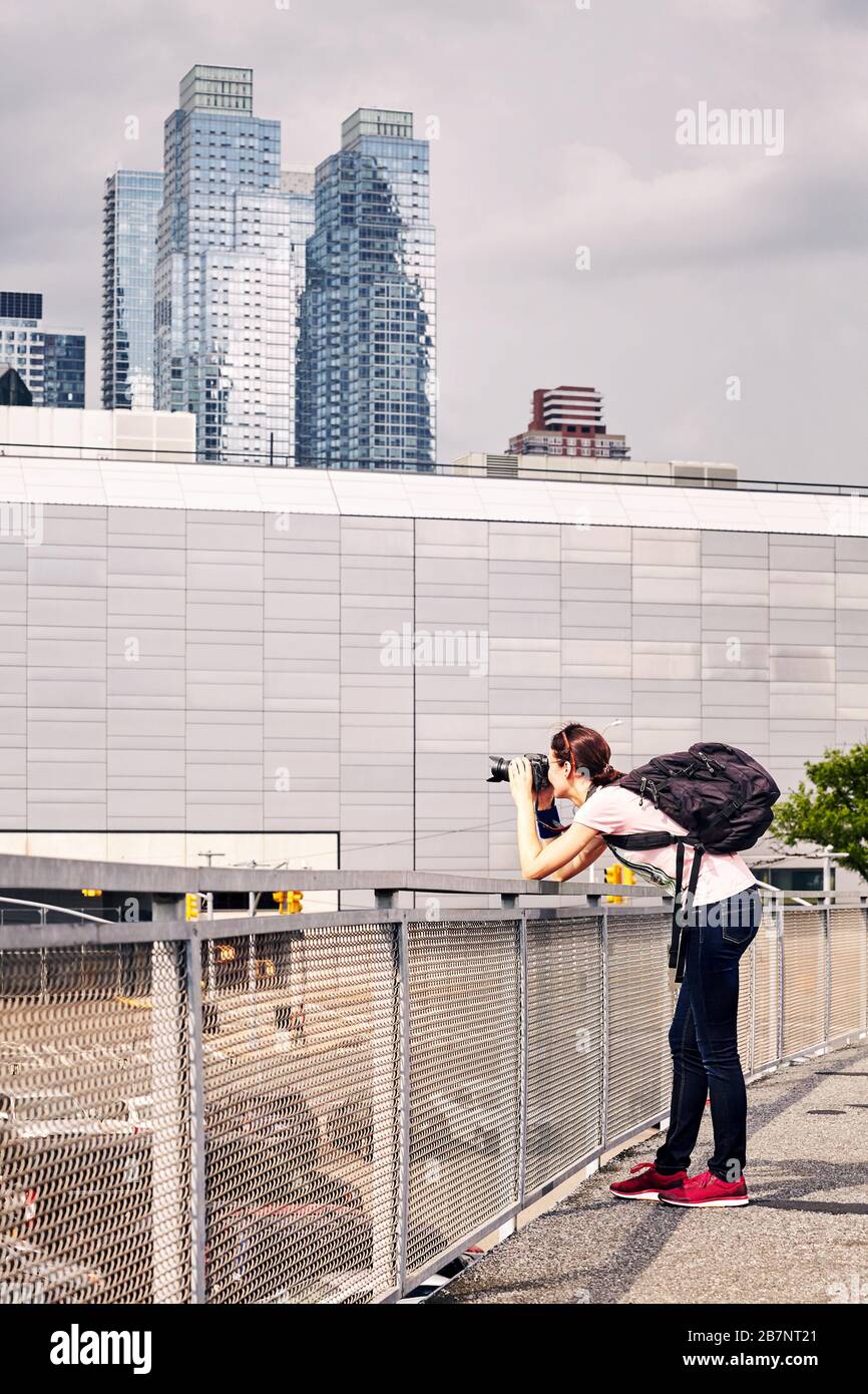 Female photographer with backpack takes pictures of architecture in New ...