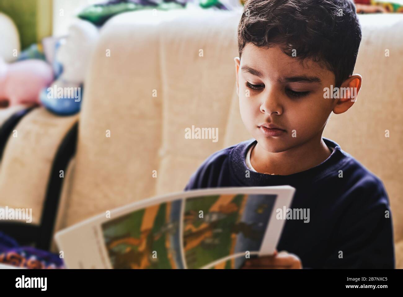 A little schoolboy doing homework. Reading book. Authentic view of a ...