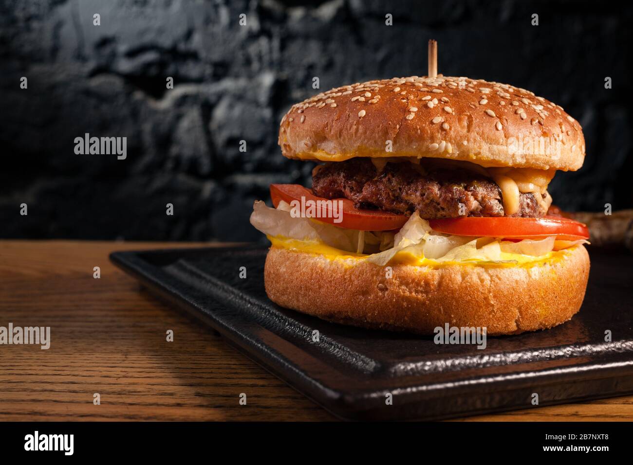 Appetizing burger on a wooden table and stand side view. Against the ...