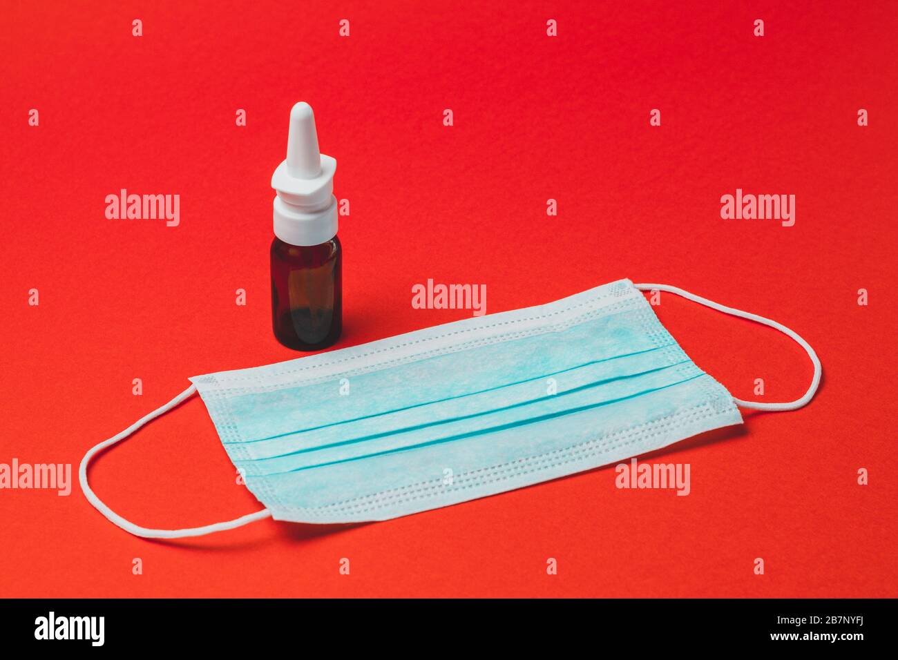 On a red background, a bottle for runny nose and allergy, medical mask ...