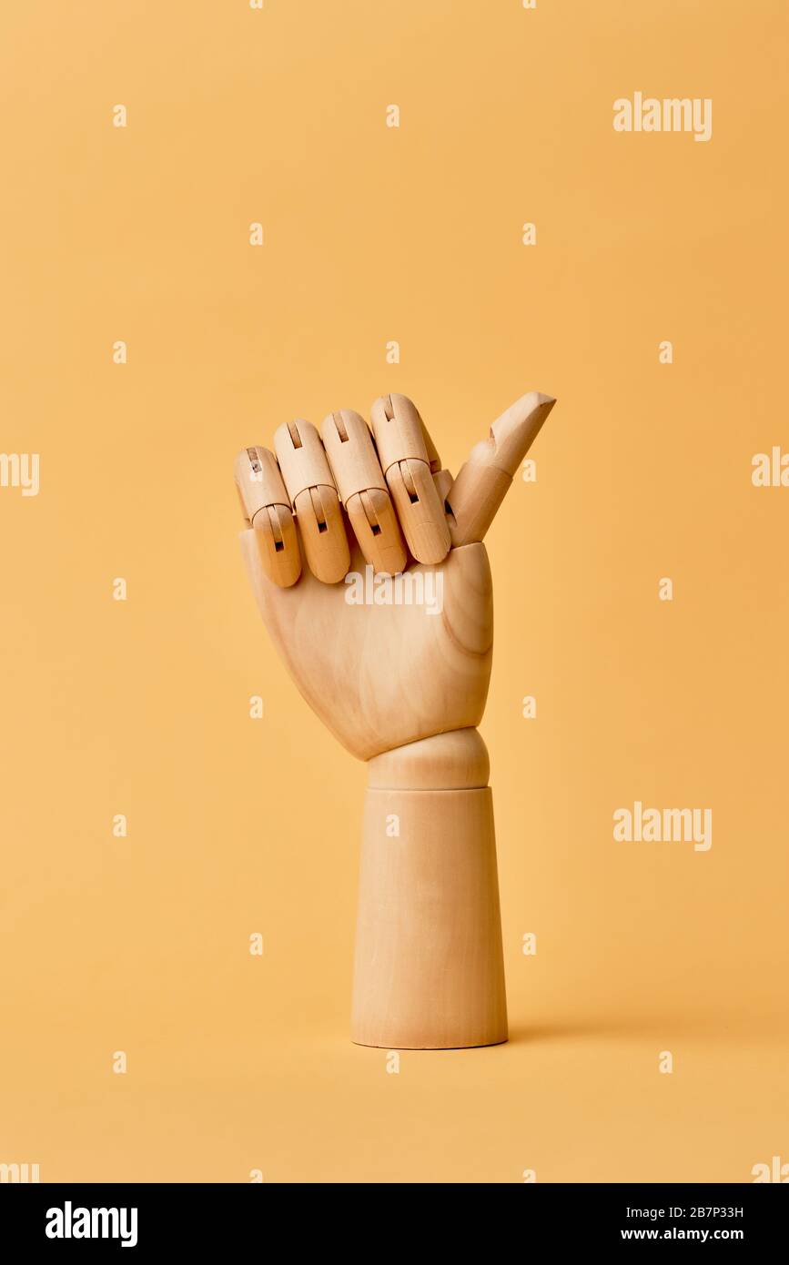 Wooden human hand with thumb raised up isolated on orange background ...
