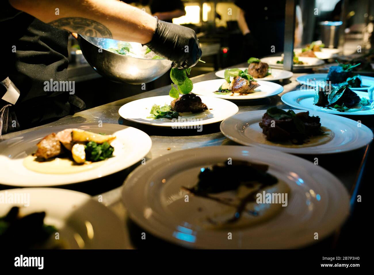 Chef adding some vegetables on a top of a piece of meat during it's ...