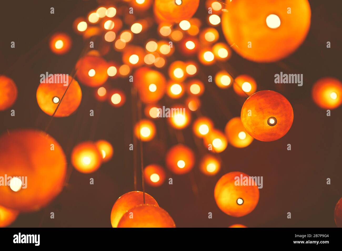 From below of hanging bright glowing red round lanterns on dark blurred ...