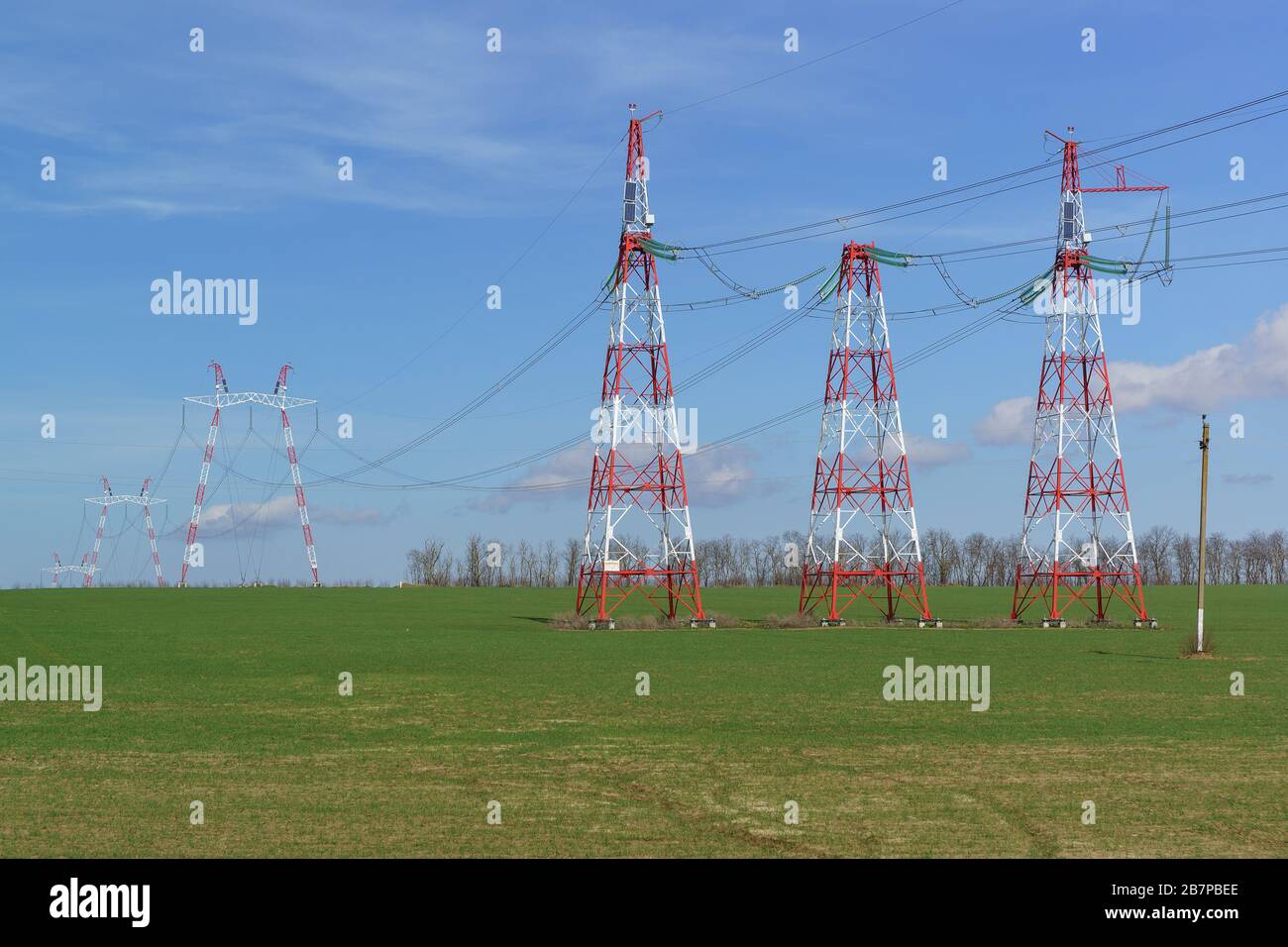 Supports power lines are in the field. Red and white against a bright ...