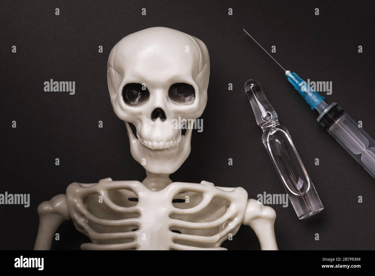 Human skeleton, syringe and ampoule on a black background, top view ...