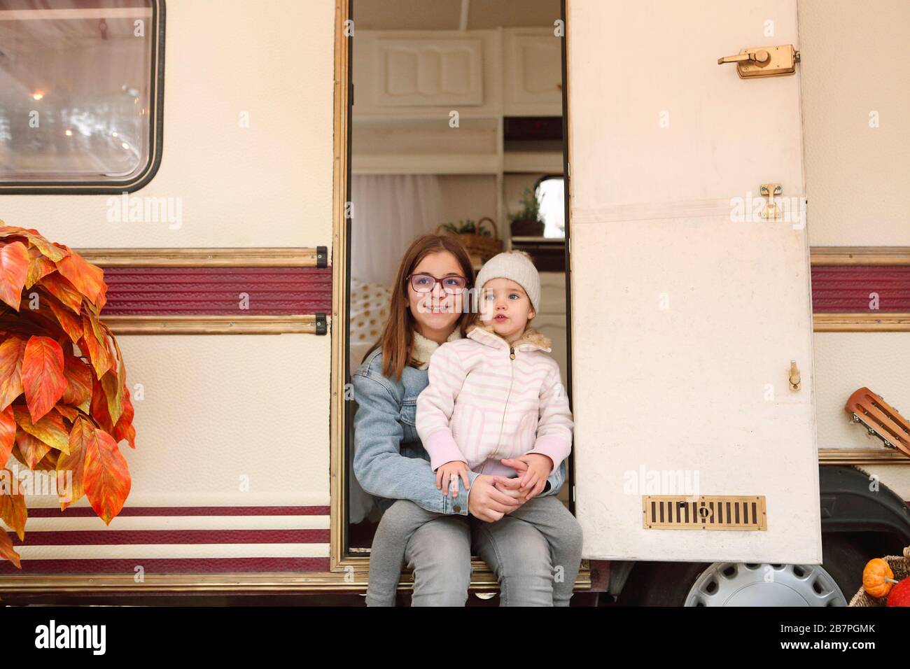 Little girls smiling while sitting in caravan in autumn Stock Photo - Alamy