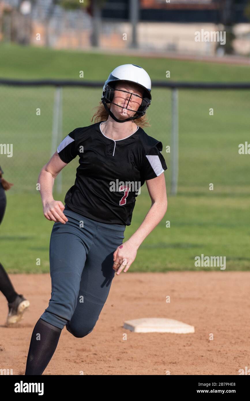 High school female softball player runs at full speed around second ...