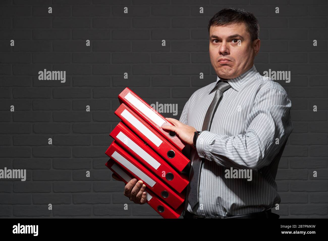 Very busy businessman closeup portrait, posing with red folders ...