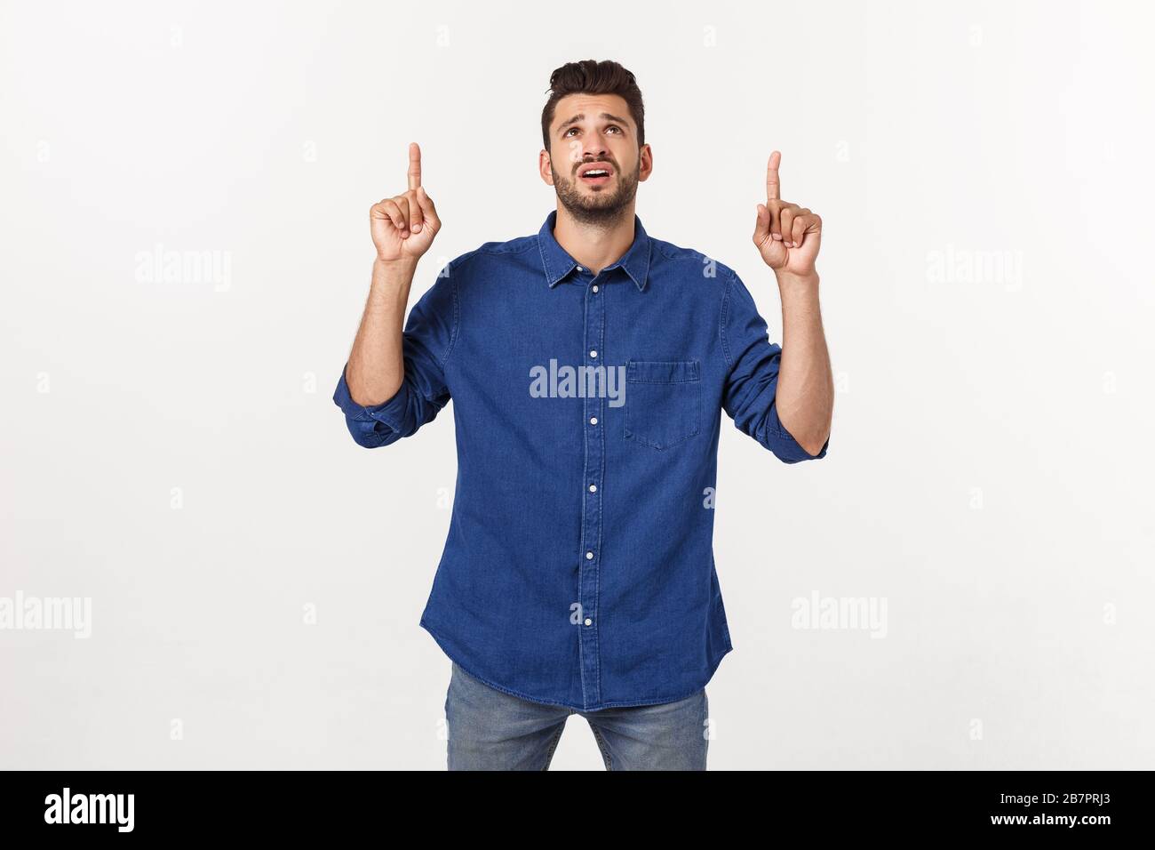Smiling young man pointing up against a white background Stock Photo ...