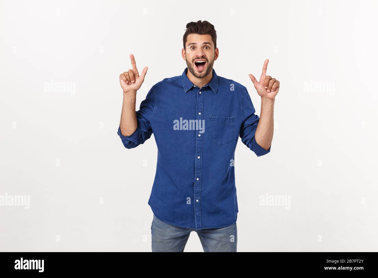 Smiling young man pointing up against a white background Stock Photo ...