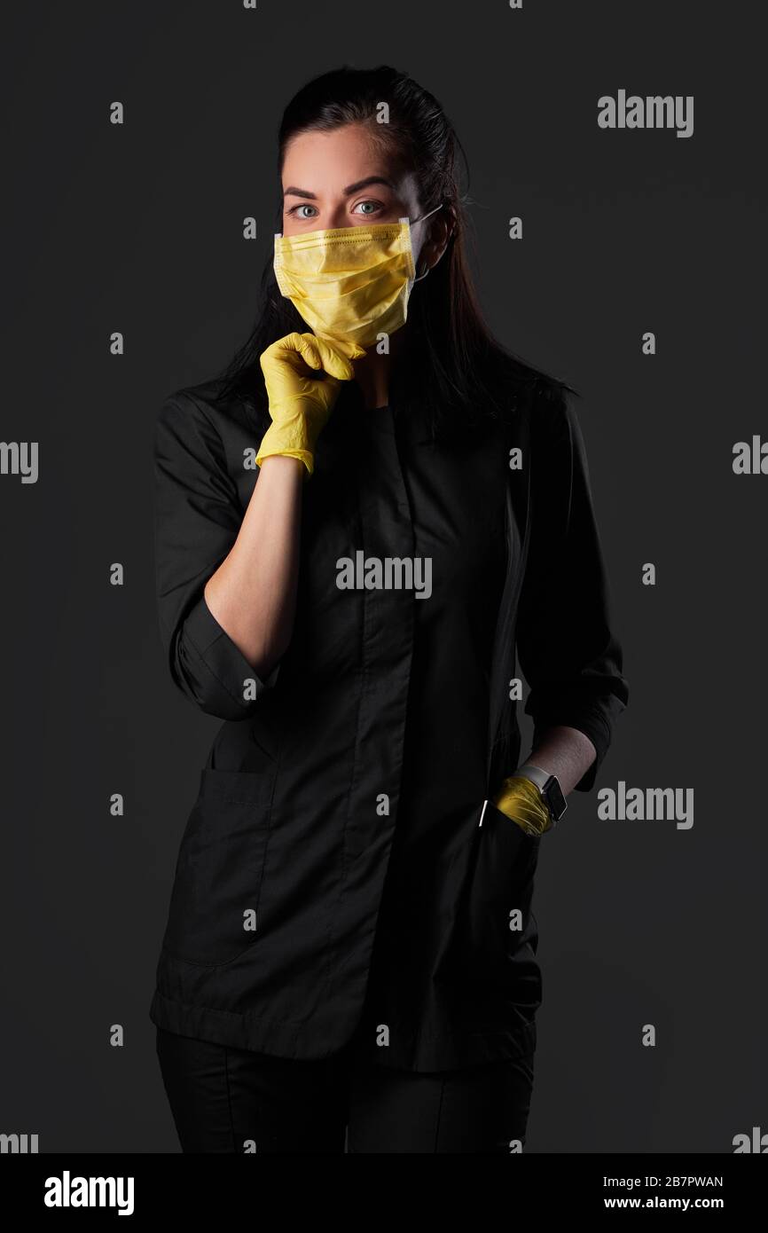 Young woman in black uniform is wearing a yellow protective medical ...