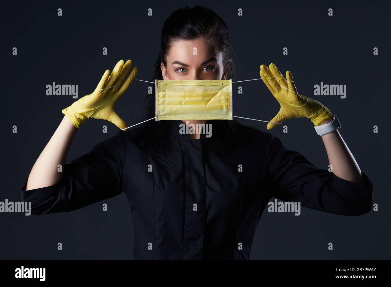 Young woman in black uniform is wearing a yellow protective medical ...