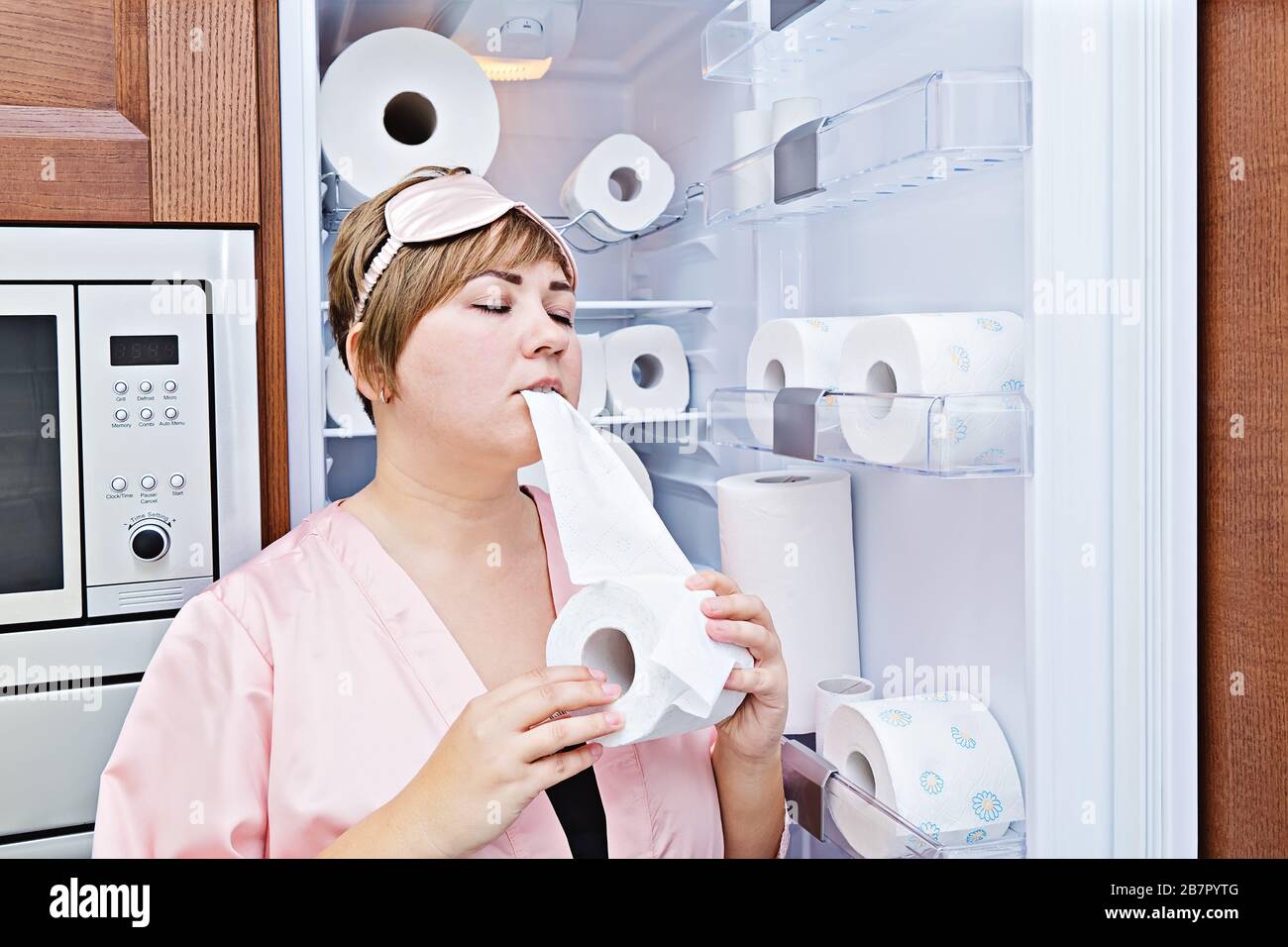 Woman In Pajamas Greedily Eats Toilet Paper Near The Fridge Filled With Wc paper Concept Of woman-in-pajamas-greedily-eats-toilet-paper-near-the-fridge-filled-with-wc-paper-concept-of