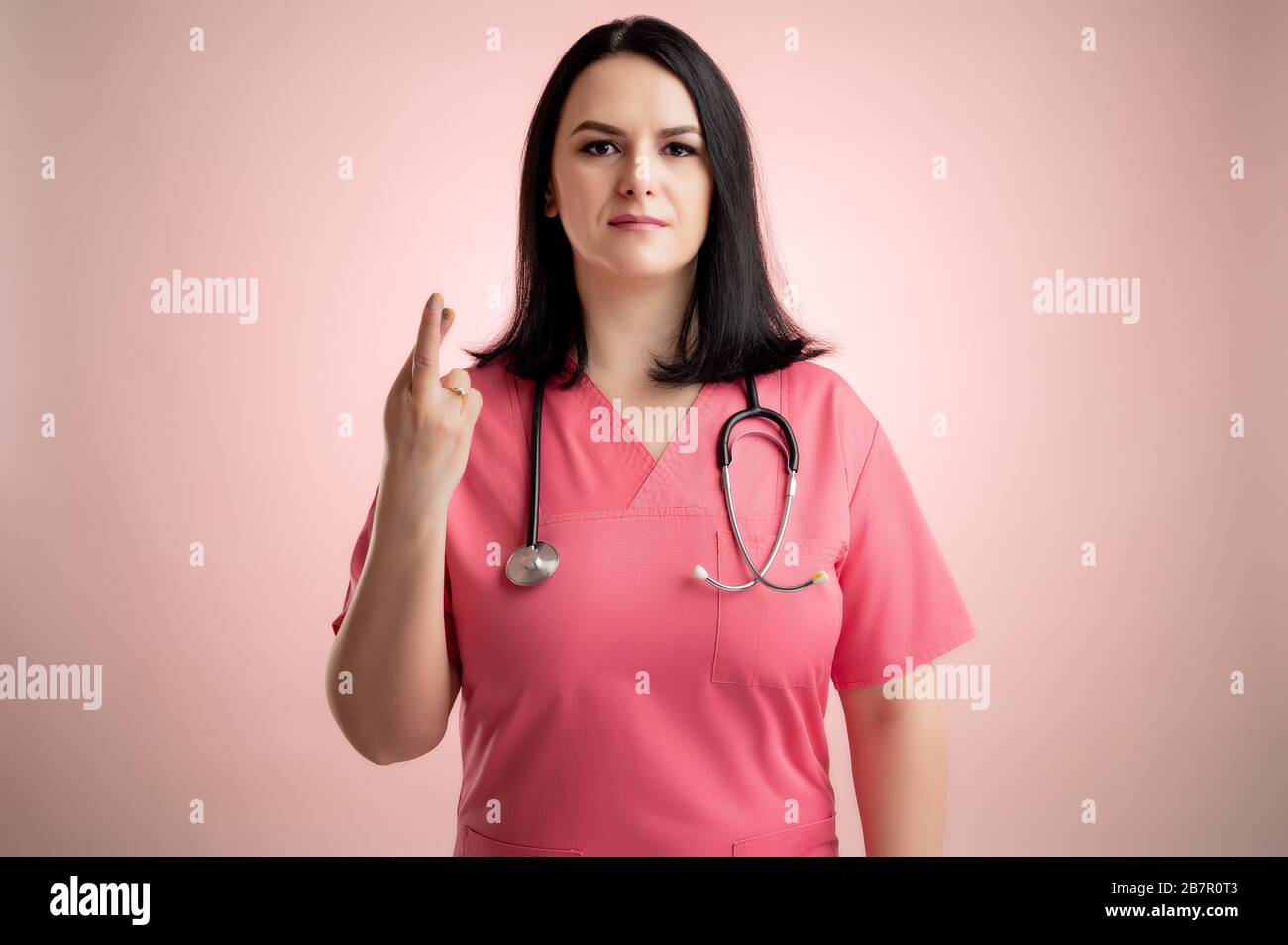 Portrait of beautiful woman doctor with stethoscope wearing pink scrubs ...