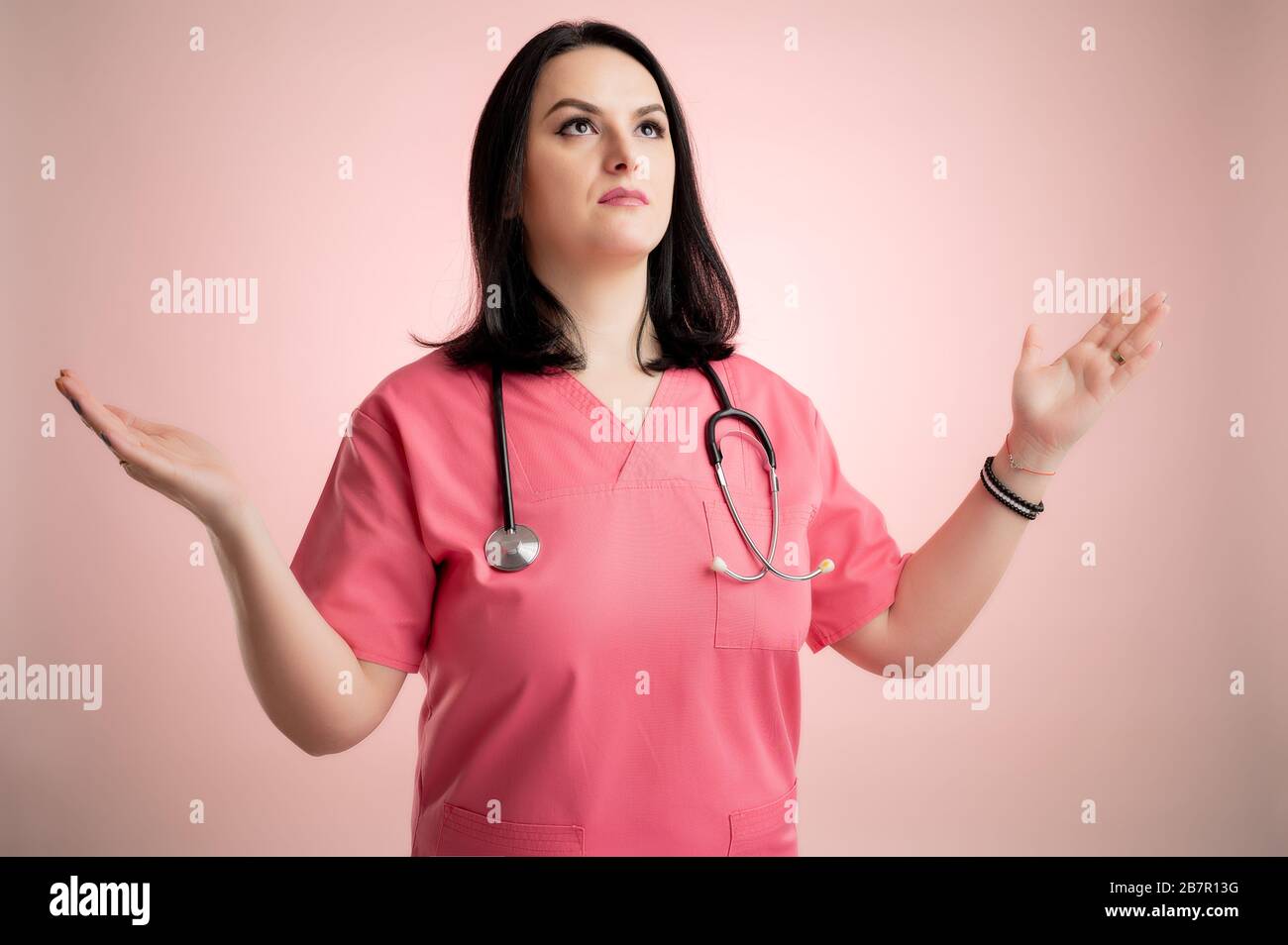 Portrait of beautiful woman doctor with stethoscope wearing pink scrubs ...