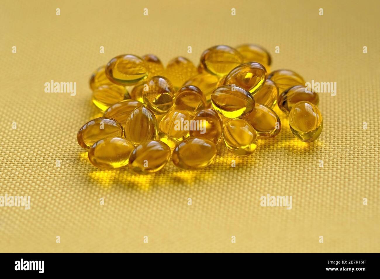 Vitamin D in yellow jelly capsules. Small yellow capsules on a yellow ...
