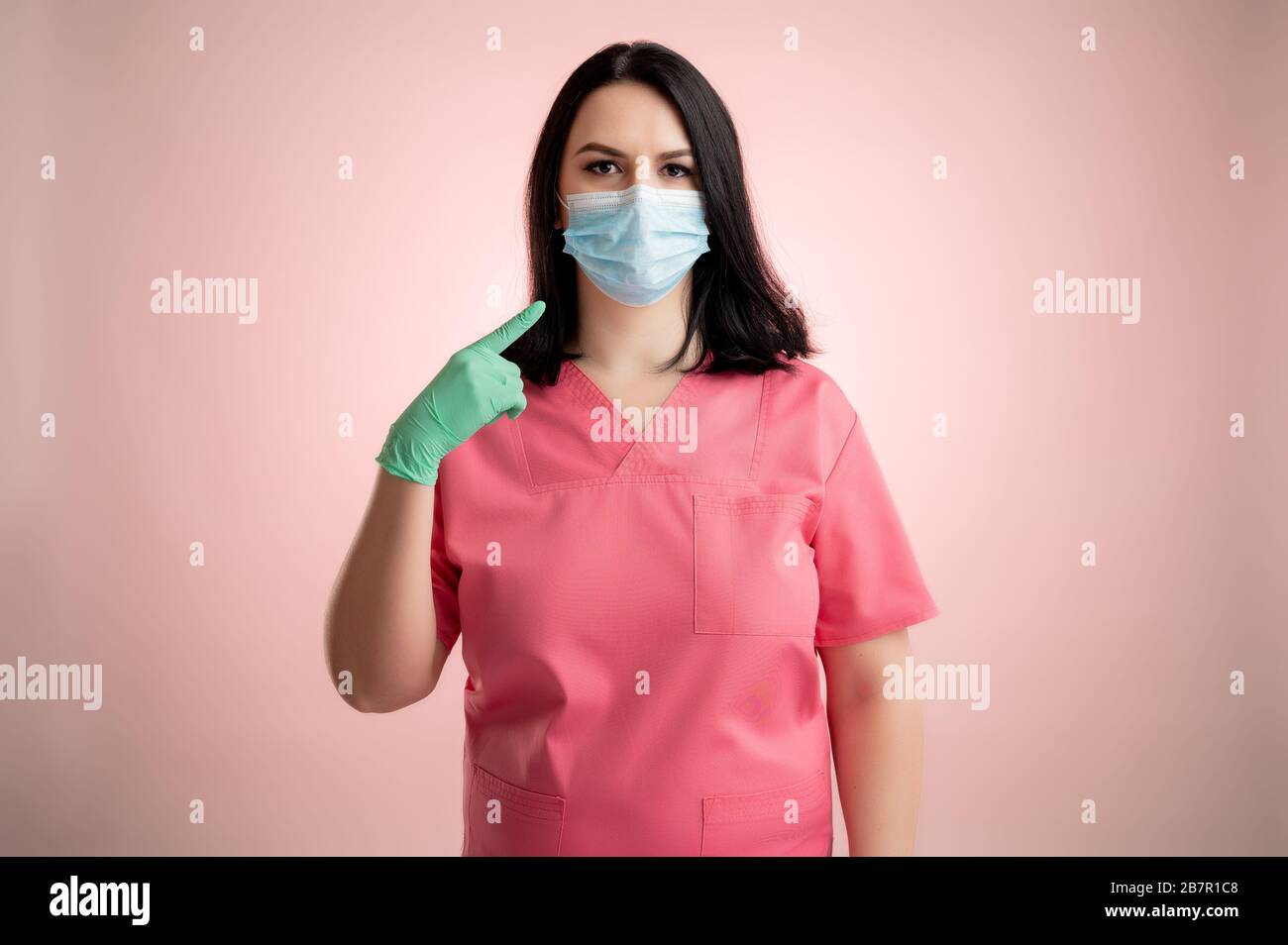 Portrait of beautiful woman doctor with stethoscope wearing pink scrubs ...