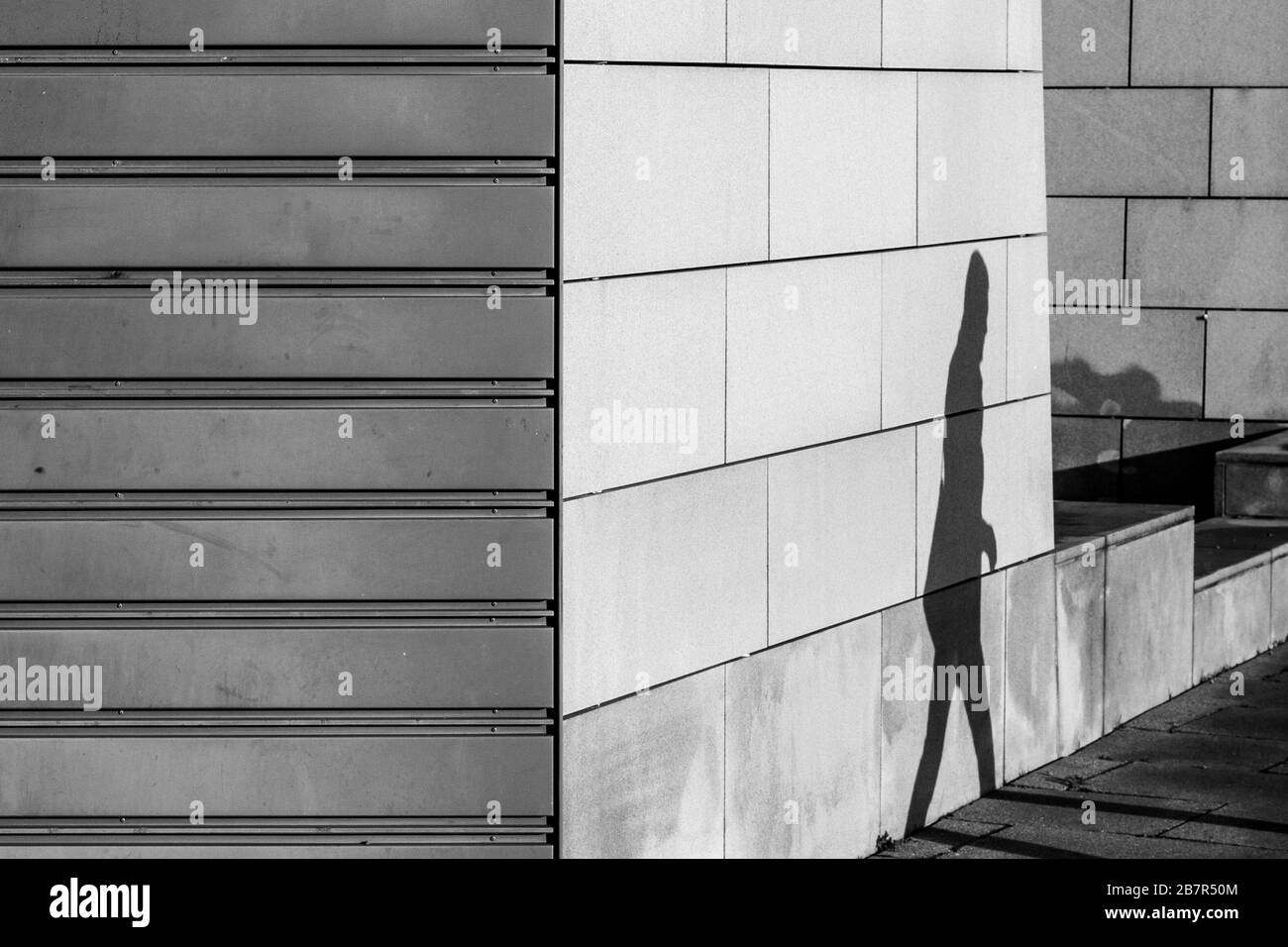 Shadow of a man walking along a building with strict lines and angles ...