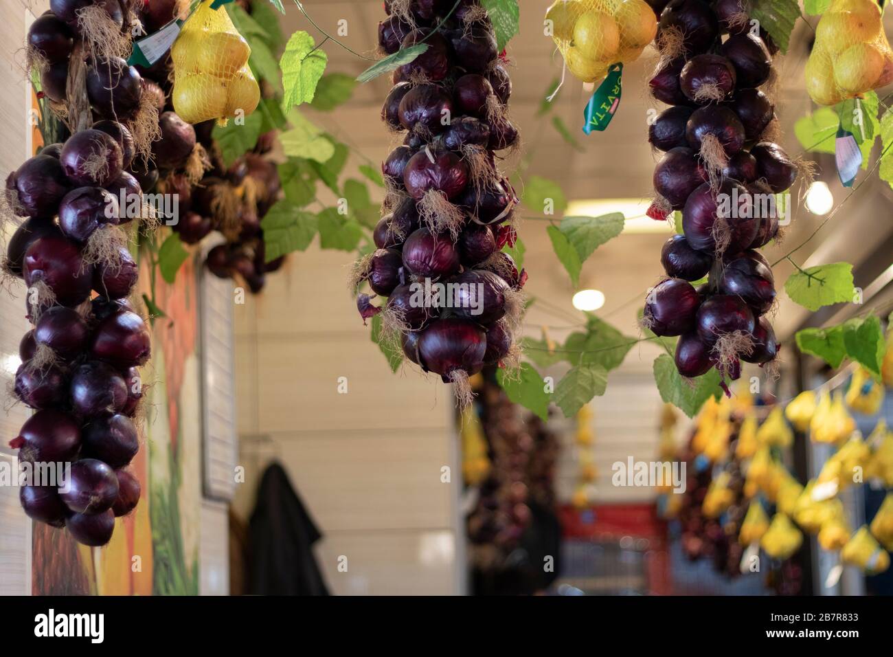 Red onions and lemons hanging in front of a greengrocer. There is a ...