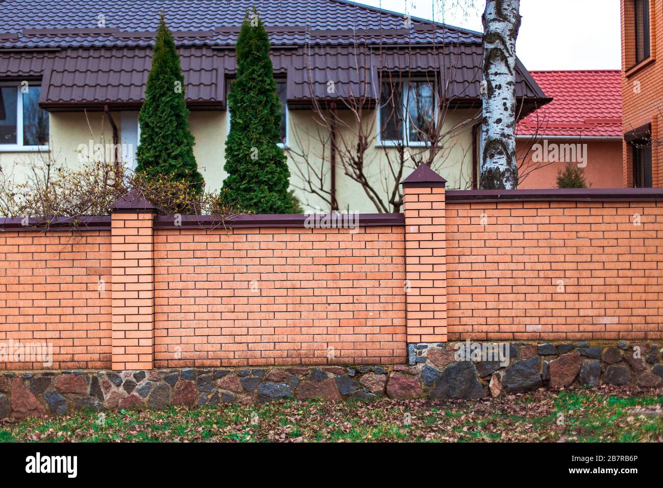 House with a brick fence and tall trees Stock Photo - Alamy