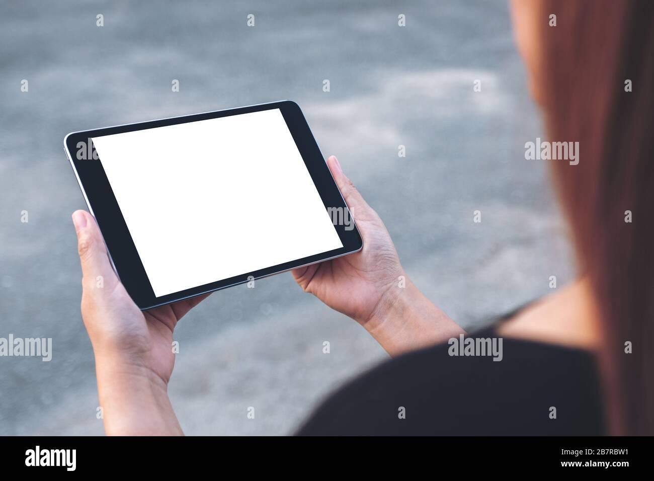 Mockup image of a woman holding and looking at black tablet pc with ...