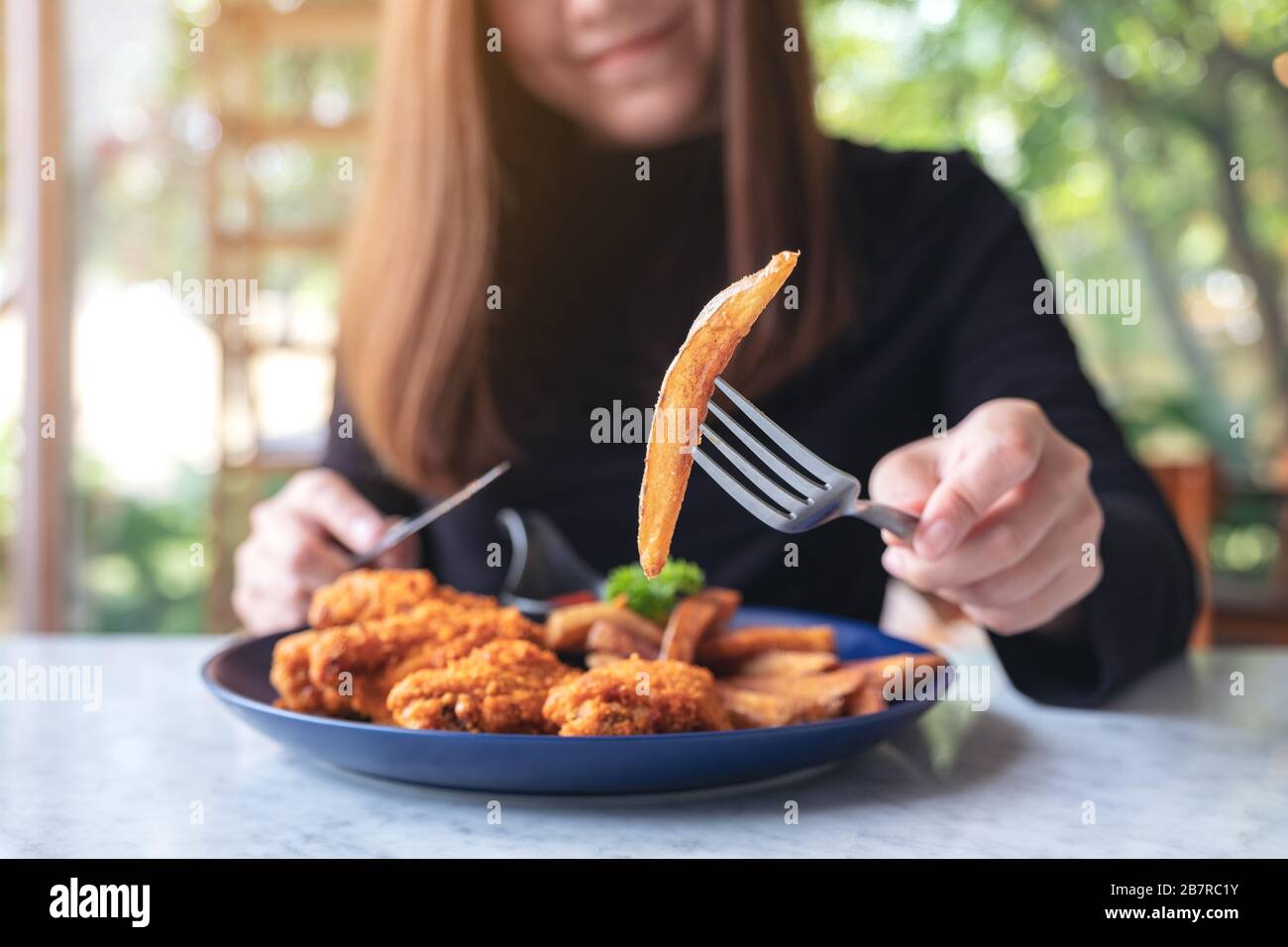 Closeup image of a woman's hand using knife and fork to eat french ...