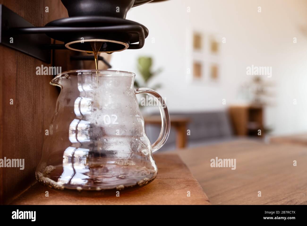 Closeup image of a drip coffee dropping into a beaker on wooden table ...