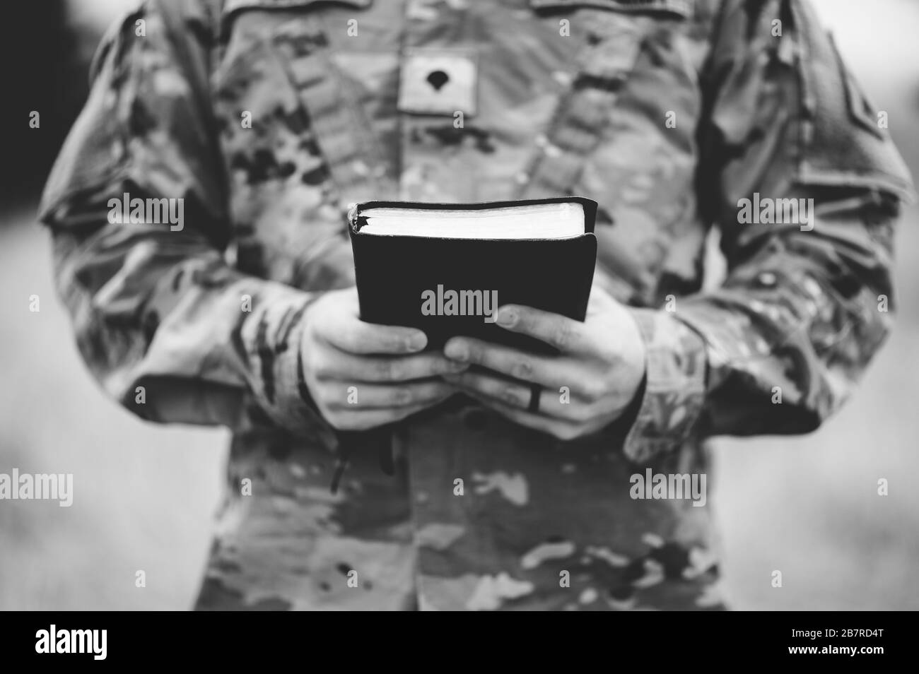 Grayscale shot of a young soldier holding a bible Stock Photo - Alamy