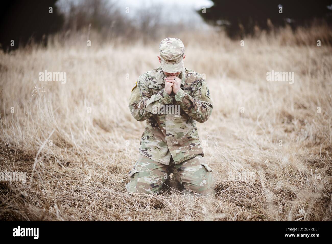 Shallow focus shot of an American soldier praying in a field while ...