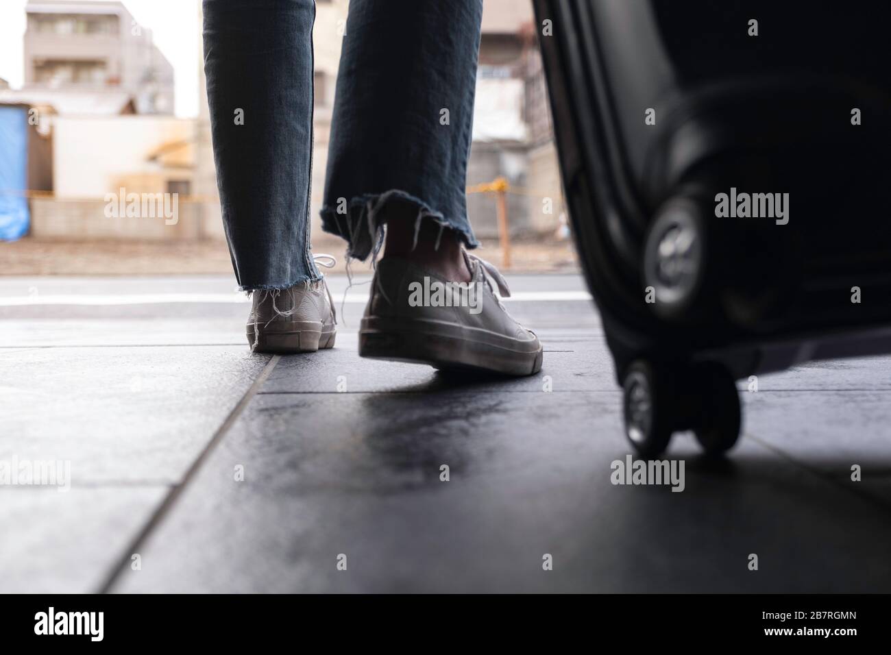 Closeup image of a woman's feet while traveling and dragging a black ...