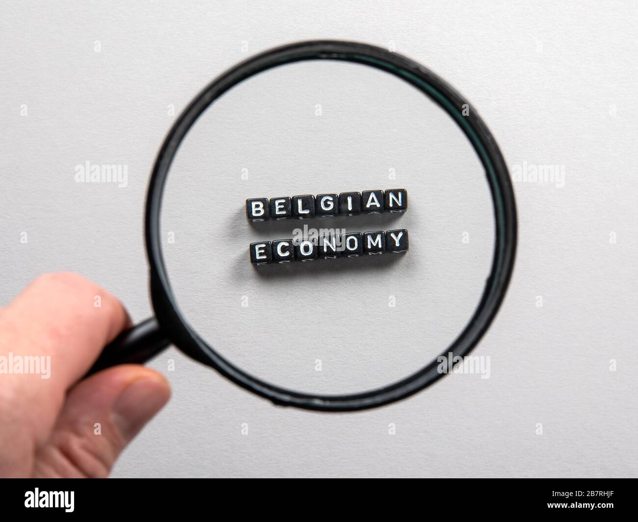 Belgian Economy. Man's hand, holding magnifying glass. Imports and ...