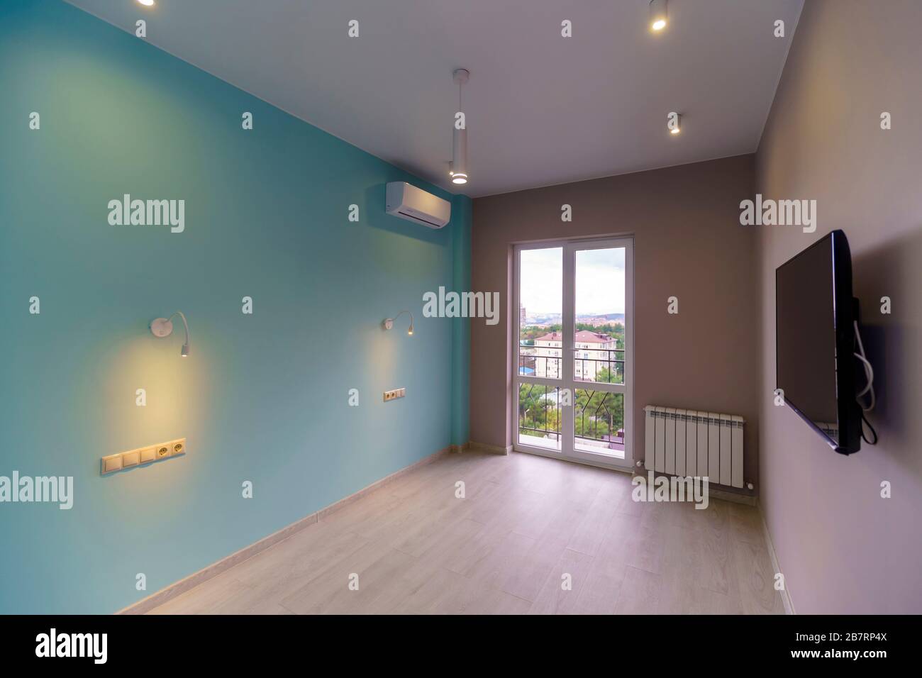 An empty room with green walls, a TV and a window in a new apartment ...