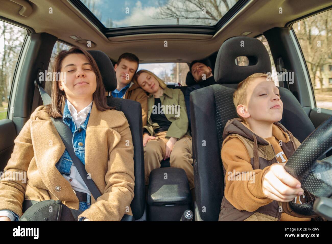 car travel fun concept. little boy driving car with adults people ...