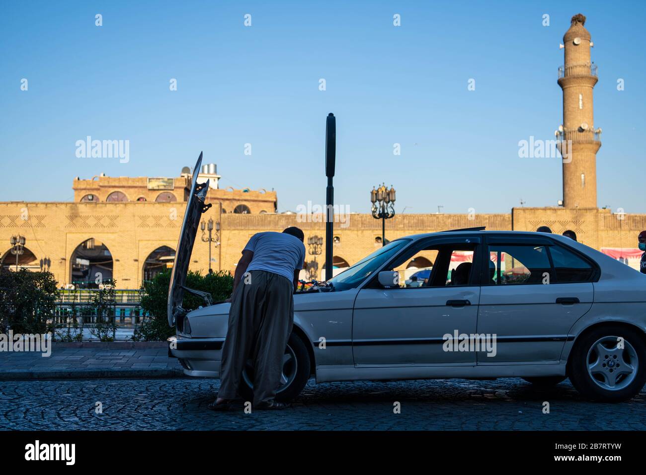 Iraq, Iraqi Kurdistan, Arbil, Erbil. man repairs his car near Shar park ...